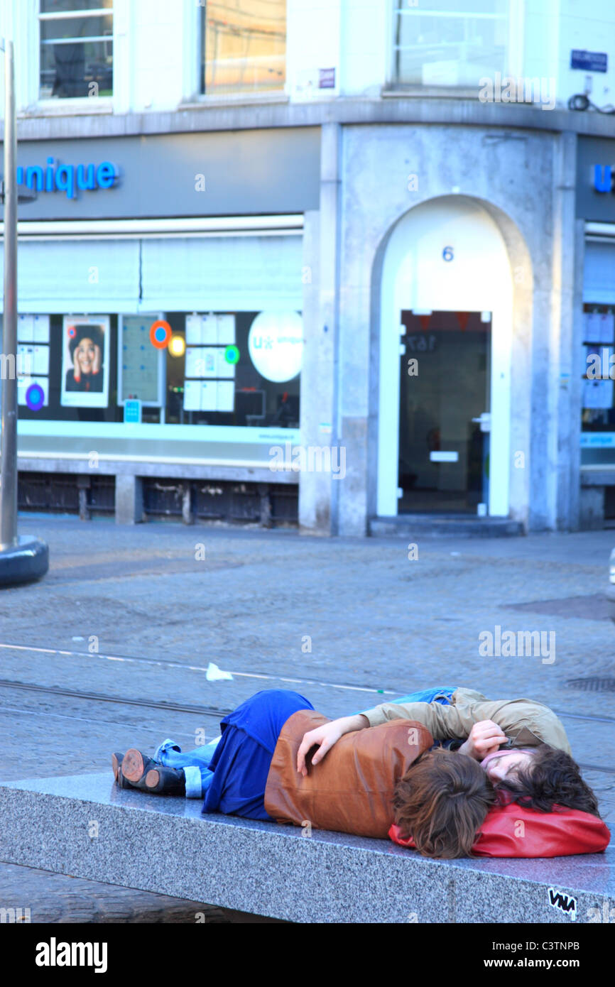 Couple sleeping in a public bench in the historic district of Amsterdam ...