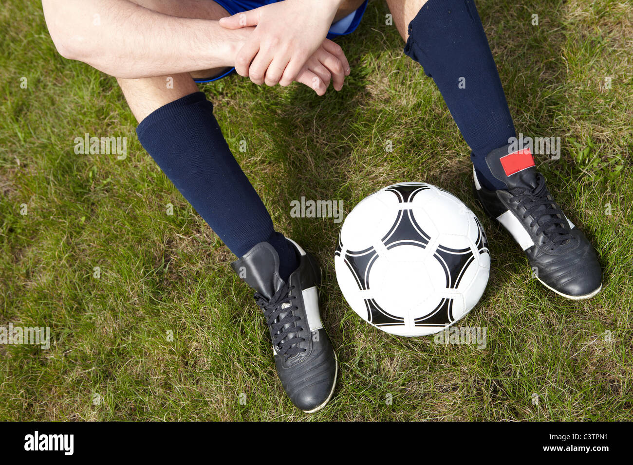 Horizontal image of seated player legs with soccer ball between Stock ...