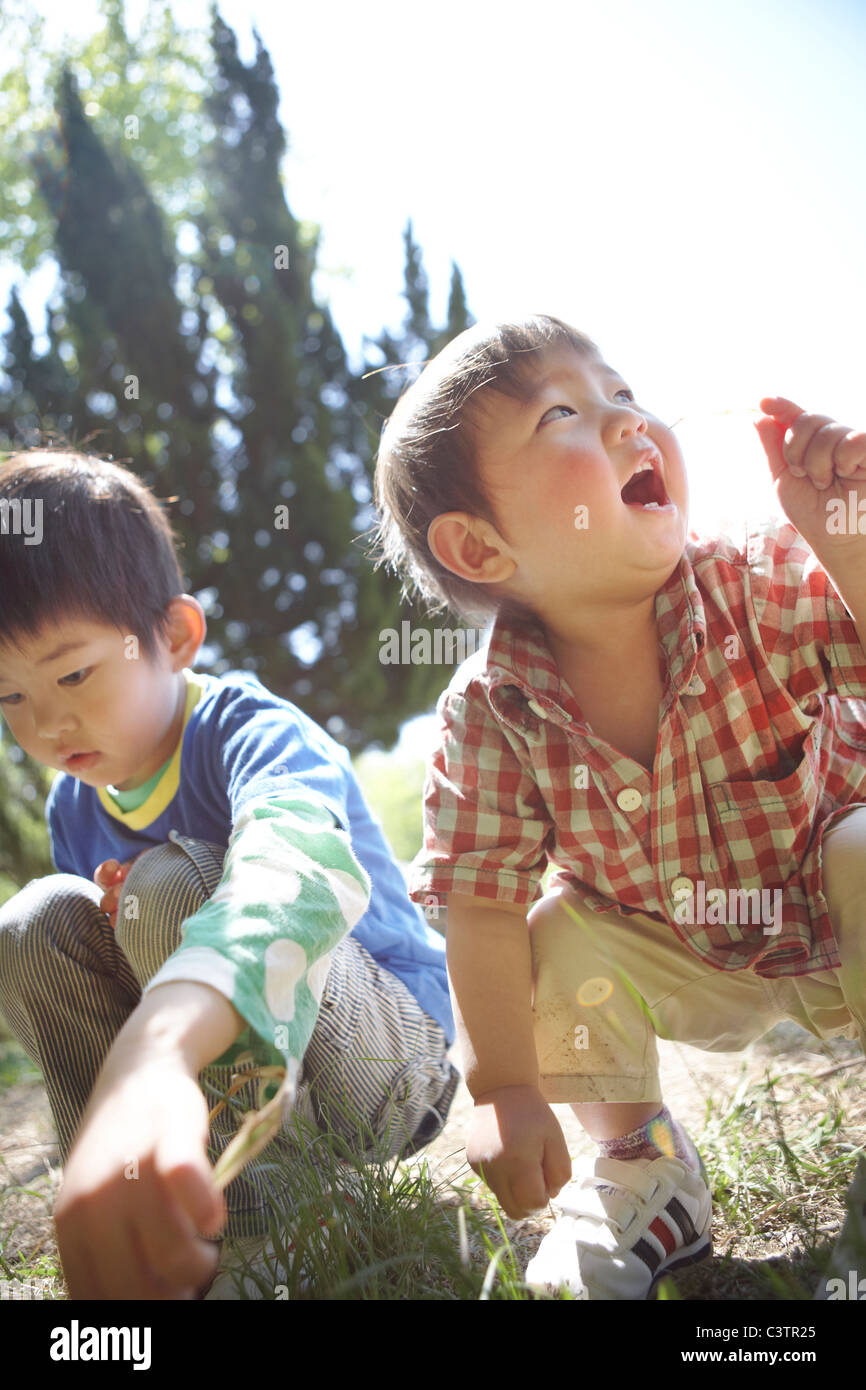 Two Boys Crouching in Grass Stock Photo - Alamy