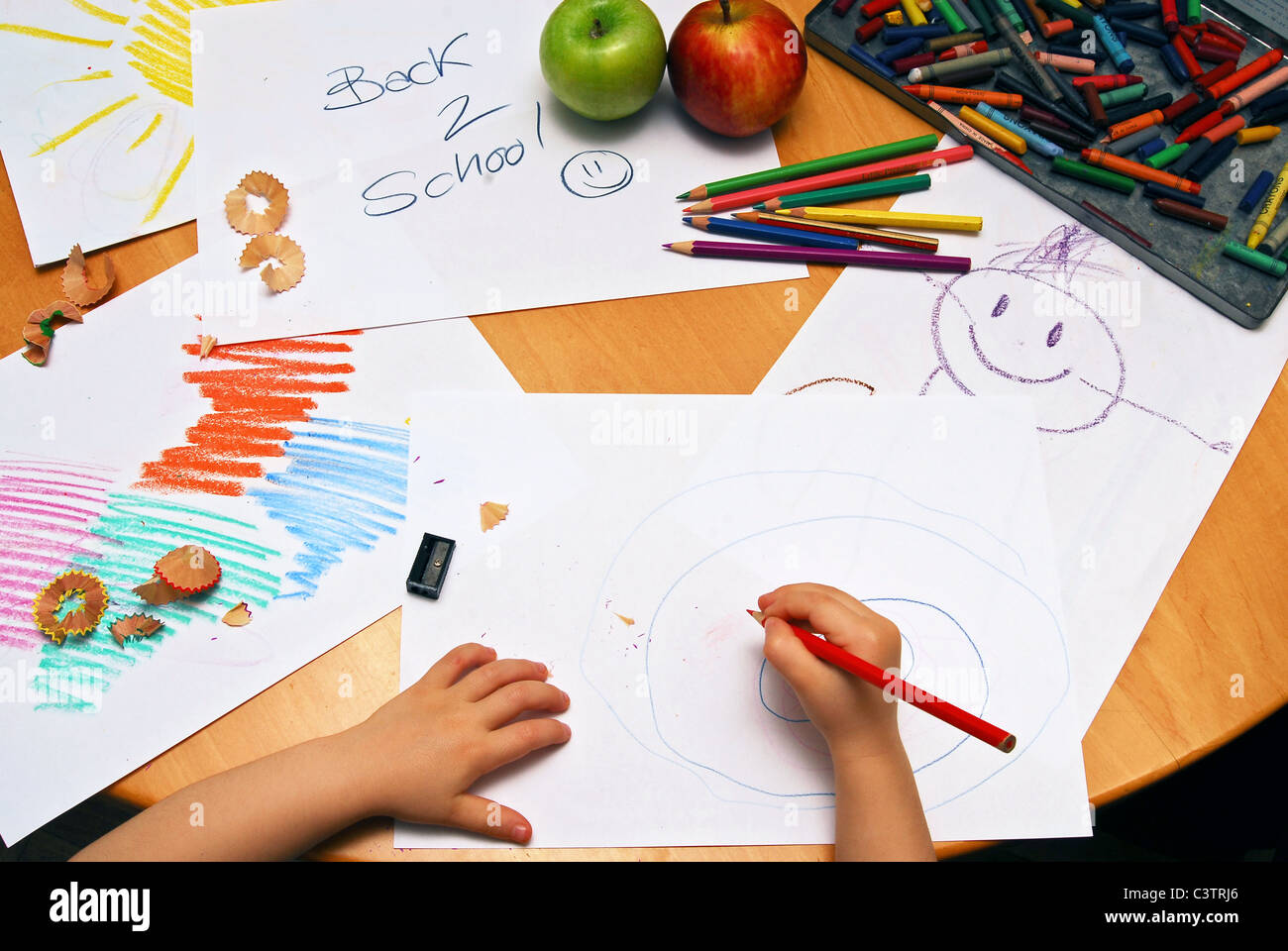 Little hands drawing between school supplies and apples Stock Photo - Alamy