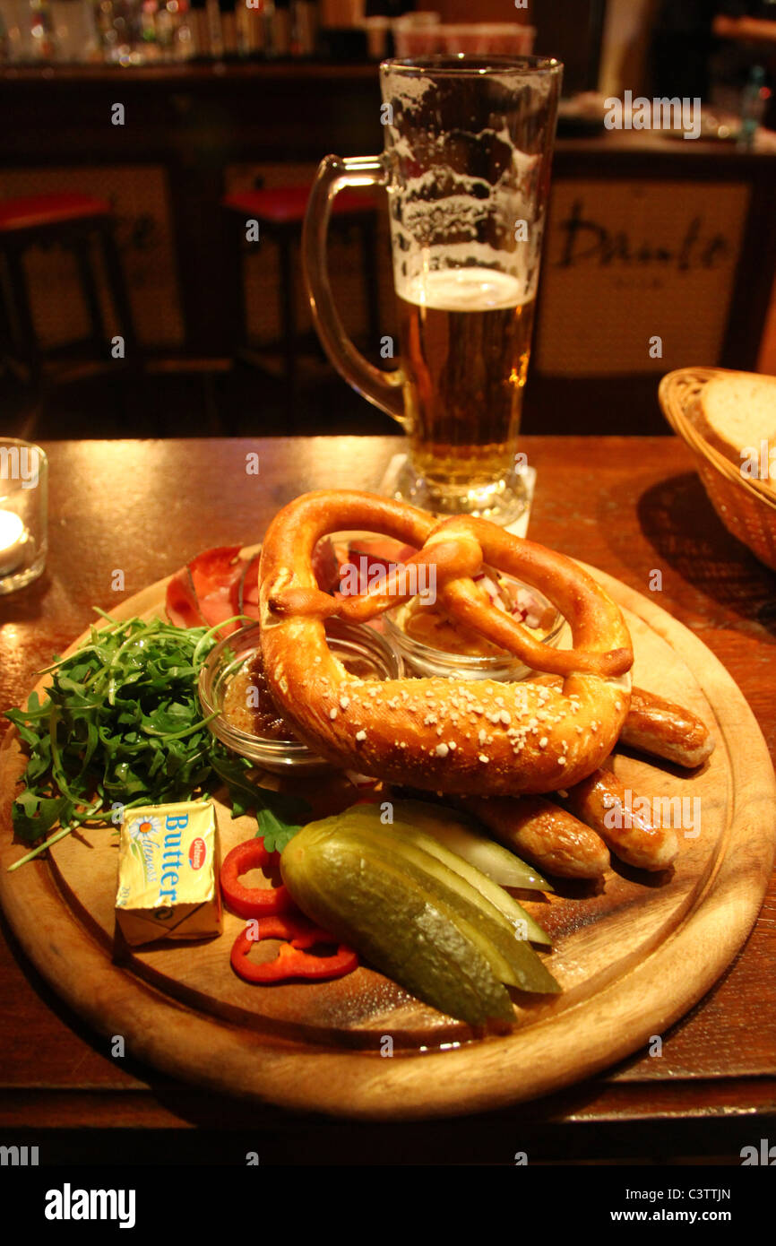 Traditional German food with bratwurst, gherkin and bread pretzel, pub ...