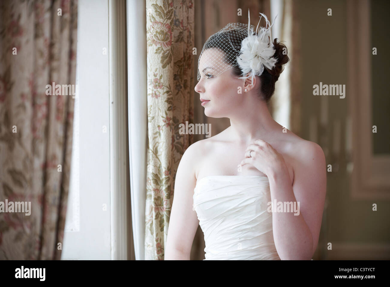 Pretty bride looking out of window and smiling on her wedding day Stock ...