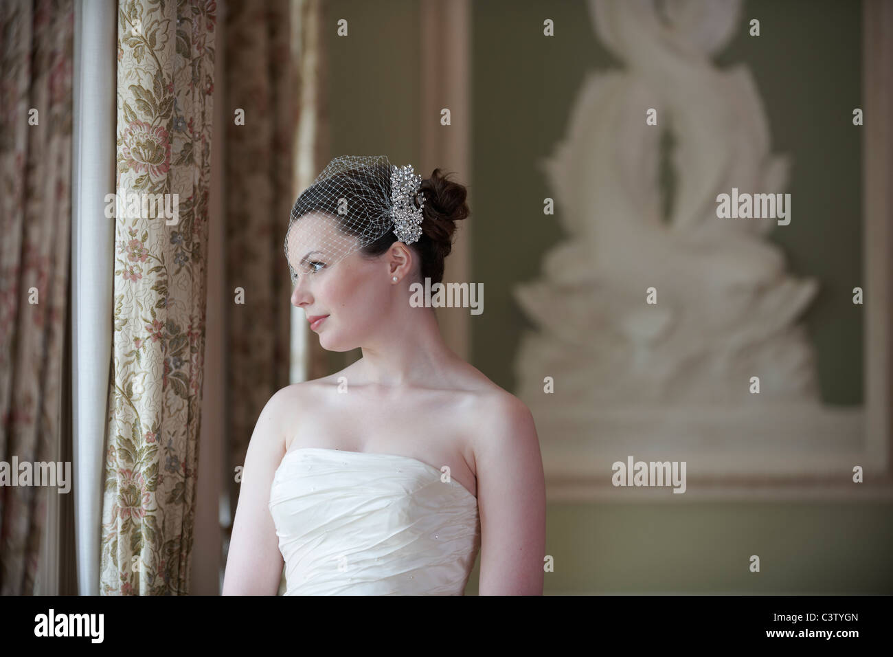 Pretty bride looking out of window and smiling on her wedding day Stock ...