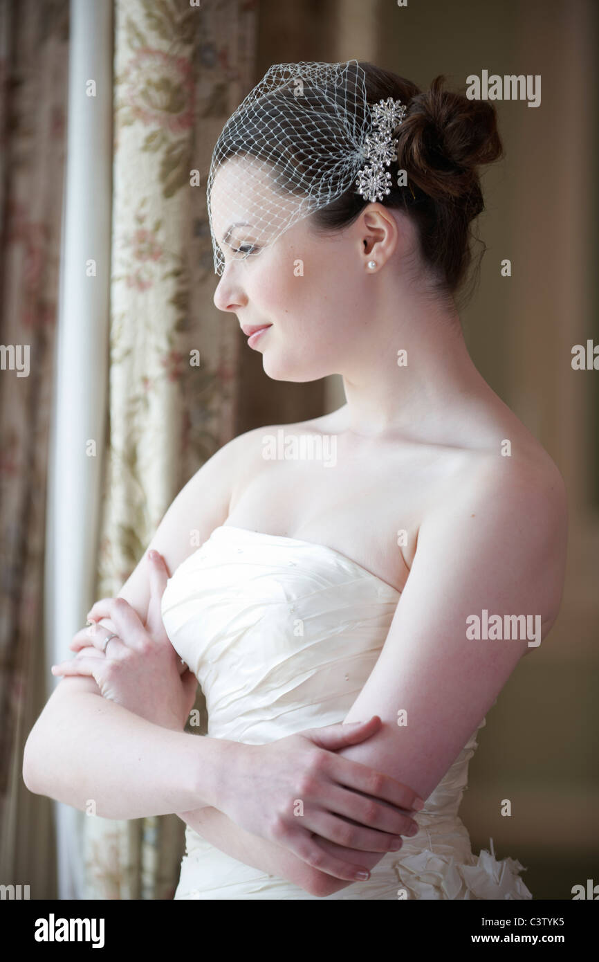 Pretty bride looking out of window and smiling on her wedding day Stock ...