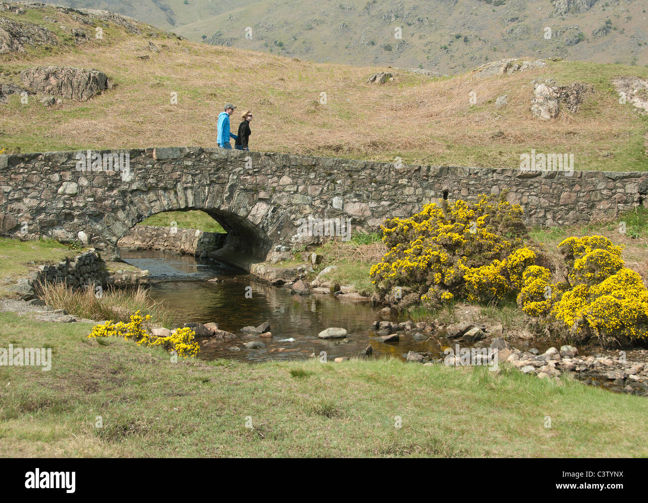 Couple walking over stone bridge in Wasdale, Cumbria Stock Photo - Alamy