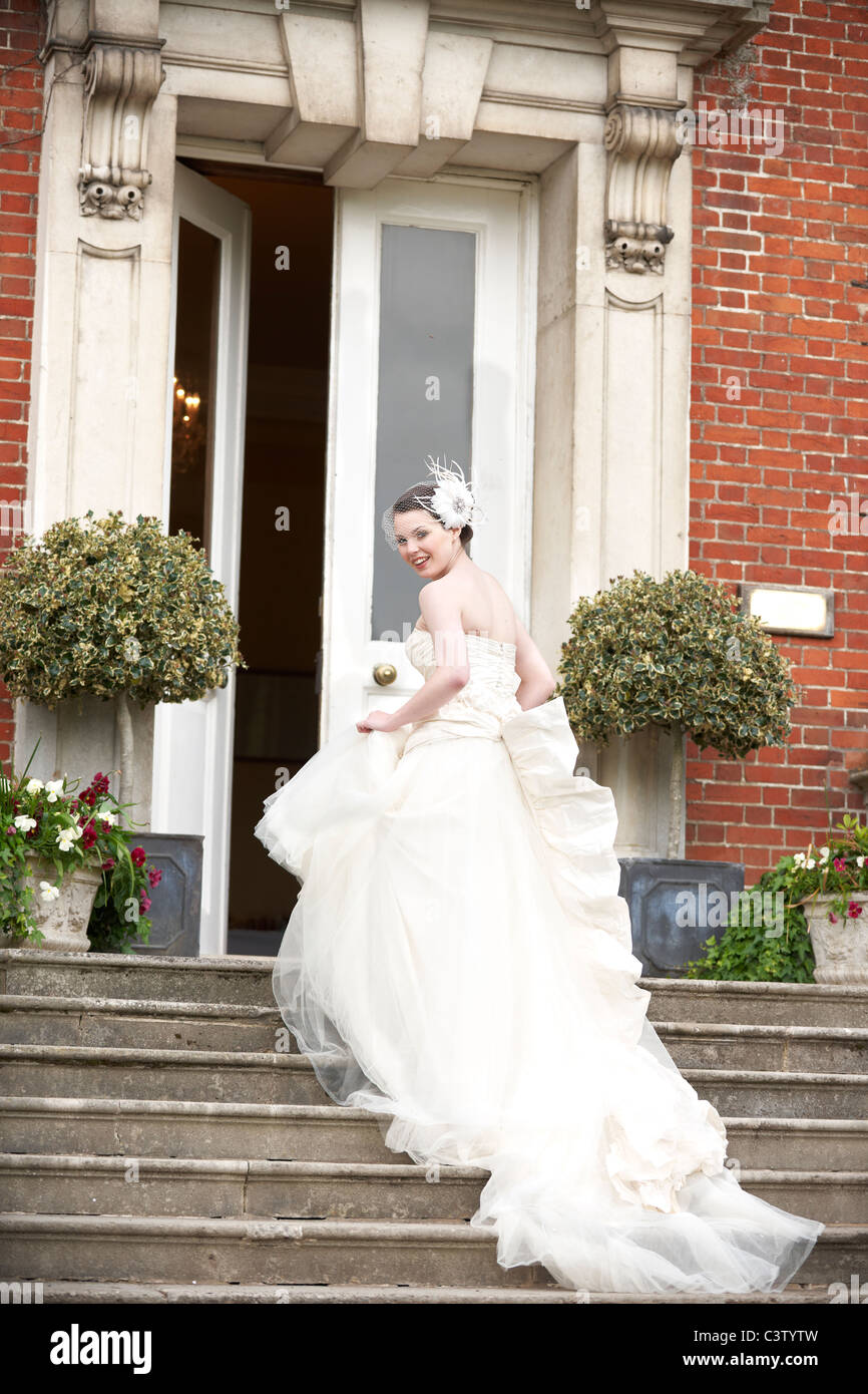Pretty bride walking up steps in her wedding dress and smiling at ...