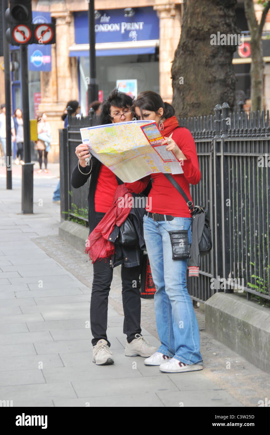 Two women tourists lost reading a folded map in London Stock Photo - Alamy