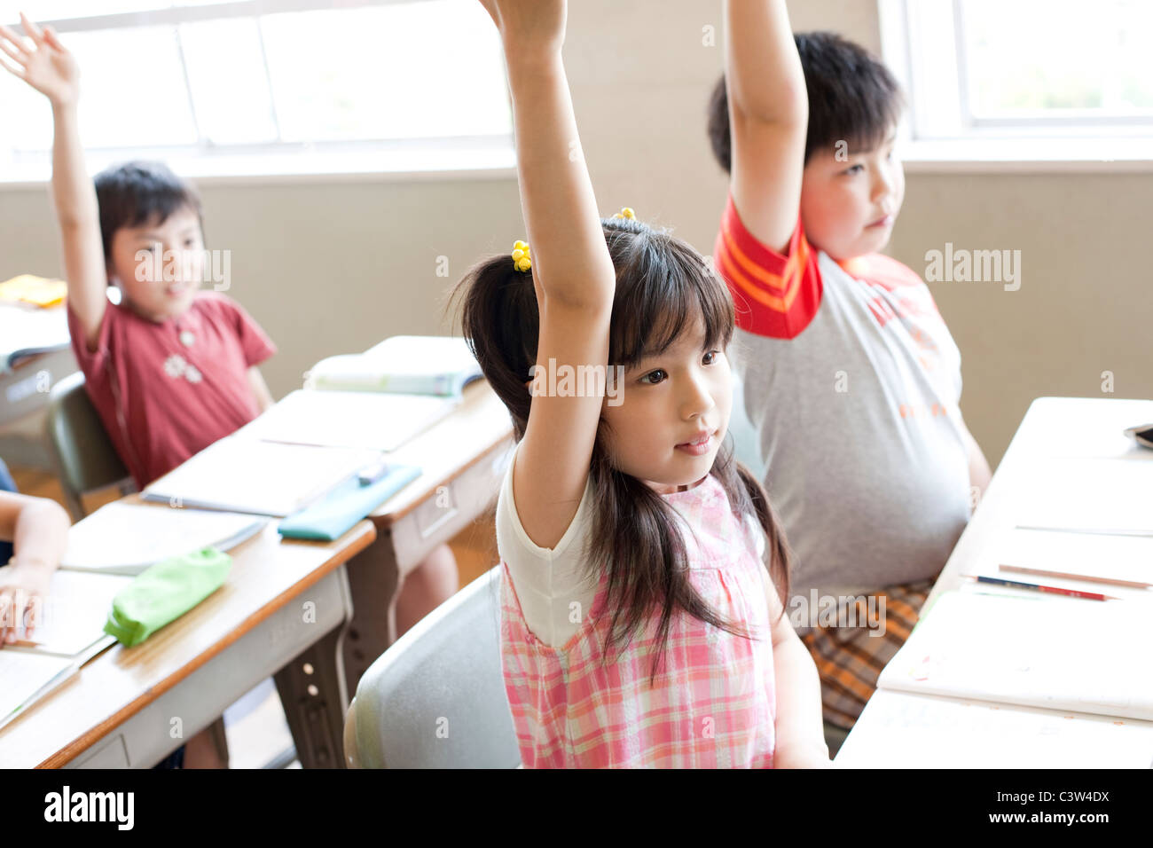 Children in classroom raising hands hi-res stock photography and images ...