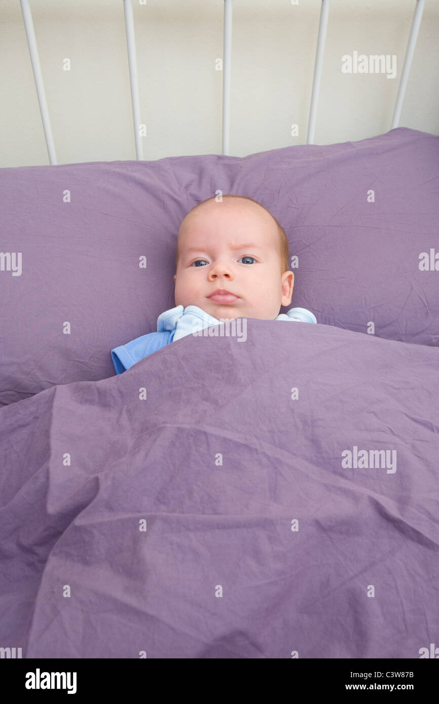Baby Ben lying in bed under a purple duvet Stock Photo - Alamy