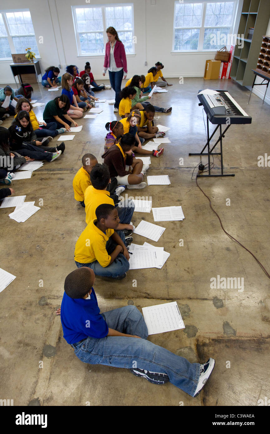 multi-ethnic group of students read sheet music before singing in music ...