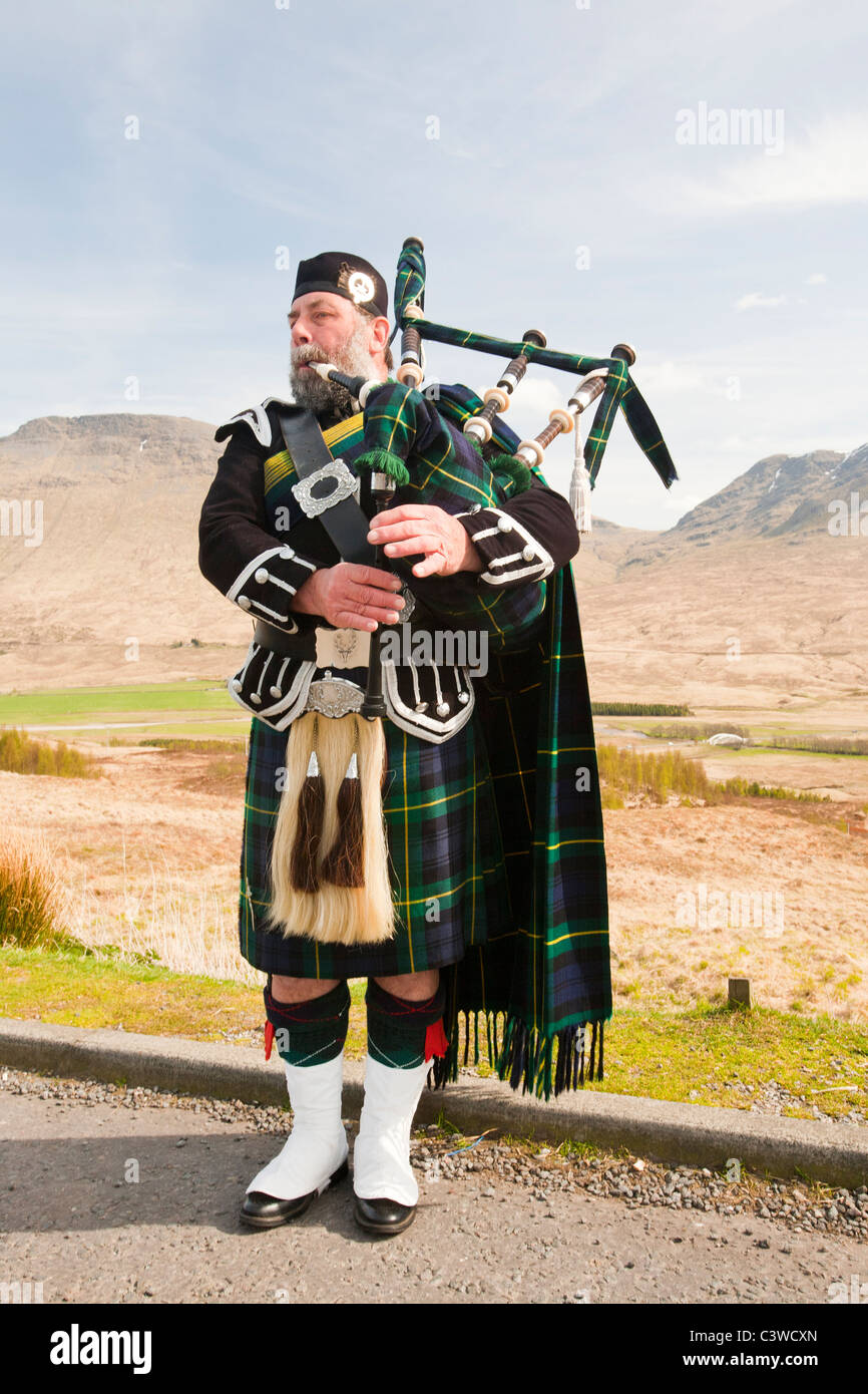 A Scottish piper in traditional dress busking on Rannoch Moor in Argyl ...
