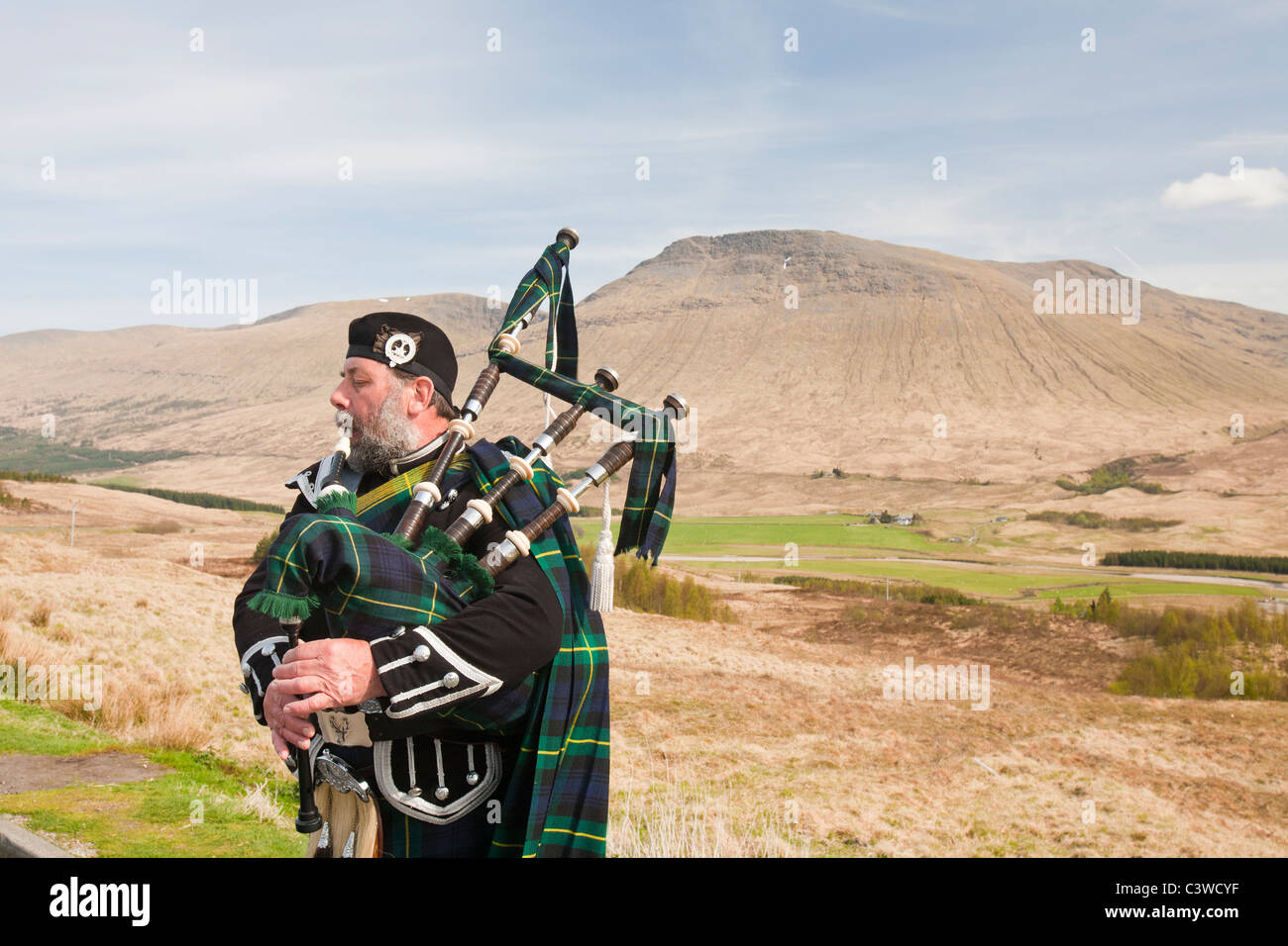 A Scottish piper in traditional dress busking on Rannoch Moor in Argyl ...