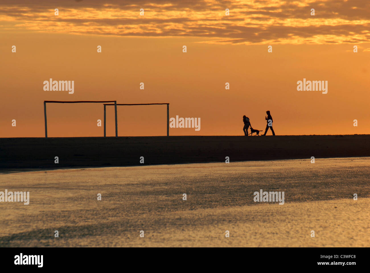 Beautiful golden sunrise seascape with soccer arcs and a running couple ...