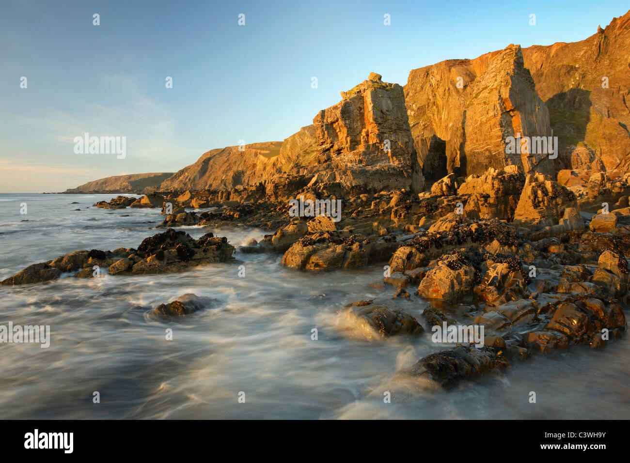 A calm summer's evening along the dramatic shores of Sandy Mouth Bay in ...