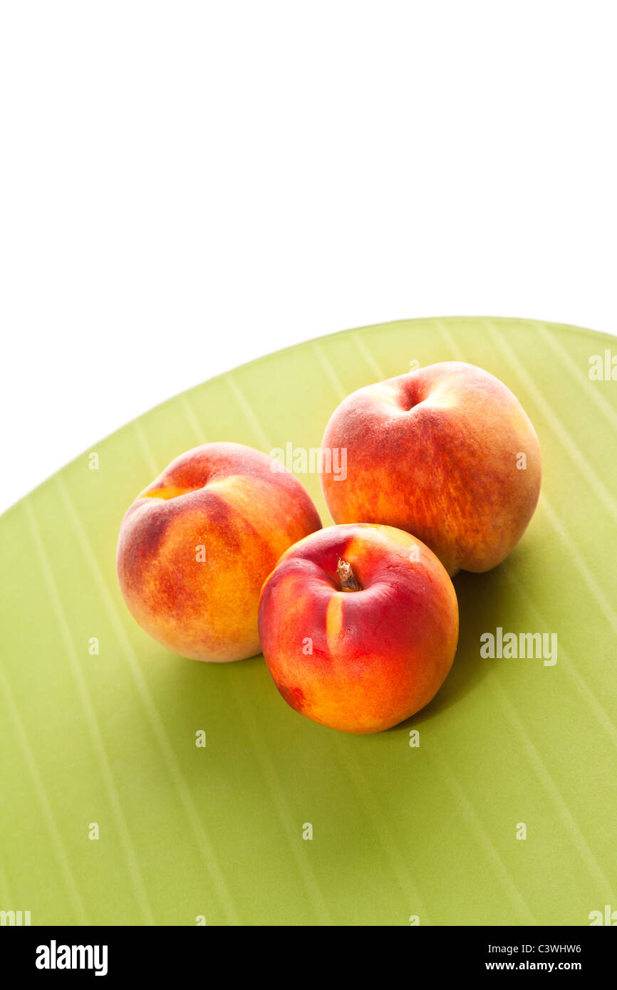 Three peaches on the green background Stock Photo - Alamy