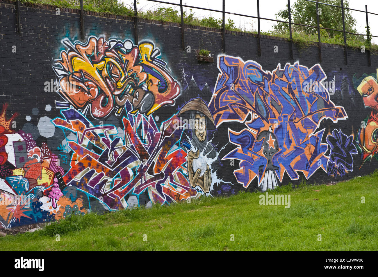 Urban graffiti artwork on brick wall of railway embankment in Cardiff ...