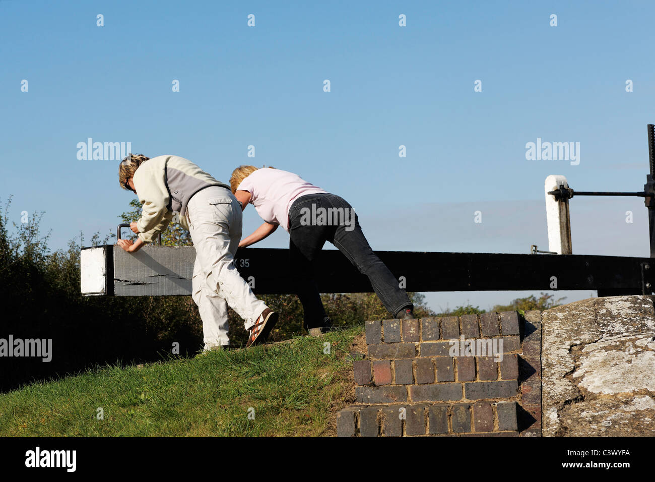 Two Women Pushing Closed A Canal Lock Gate Stock Photo - Alamy