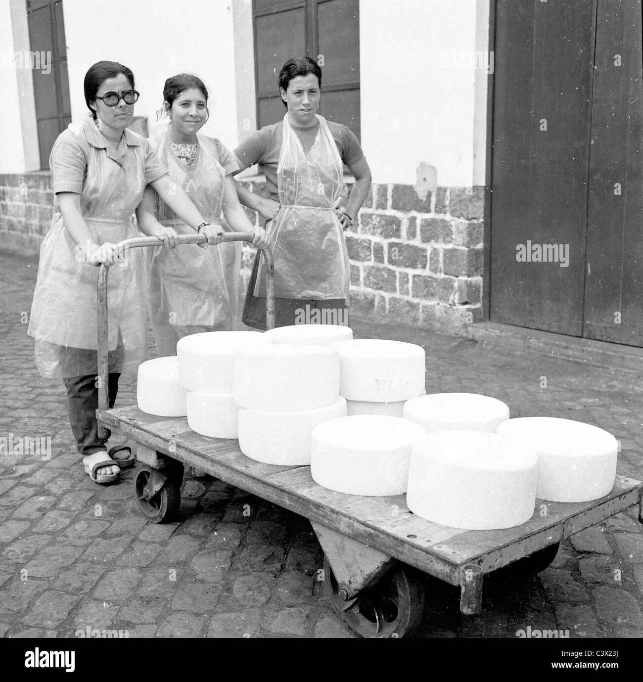 1950s, Azores. Three female factory workers stand outside the factory ...