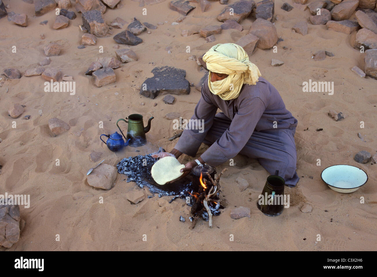 Algeria, Djanet, Sahara Desert, man of Touareg tribe baking bread in ...