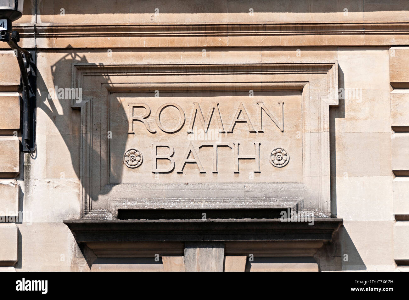 a roman bath sign in stone on the side of a street in bath somerset ...