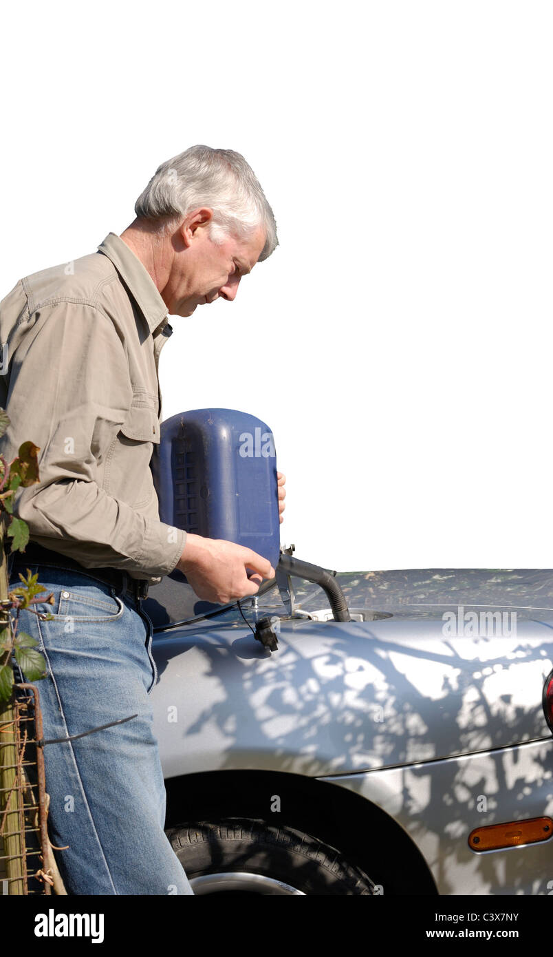 Mature man putting fuel into vehicle from a carry can. With white ...