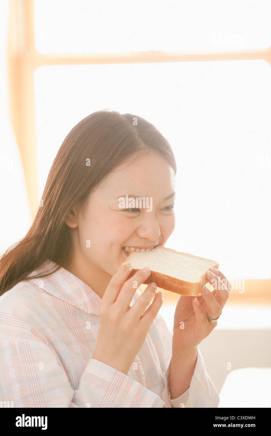 Young Woman Eating Slice of Bread Stock Photo - Alamy
