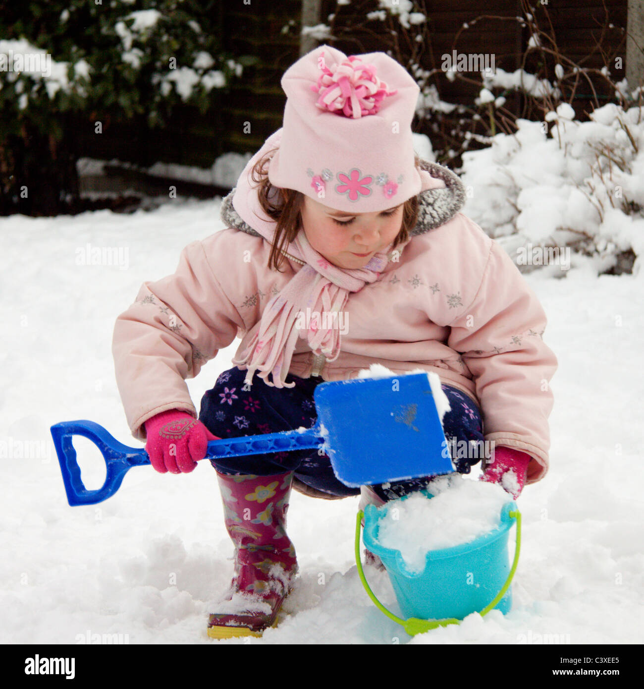 Girl playing in the snow having fun making snow castles Stock Photo - Alamy