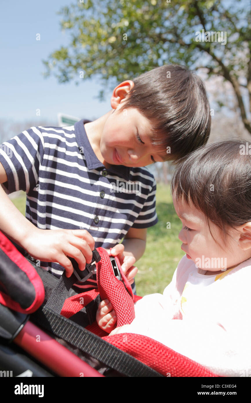 Brother Helping Little Sister with Buggy Stock Photo - Alamy