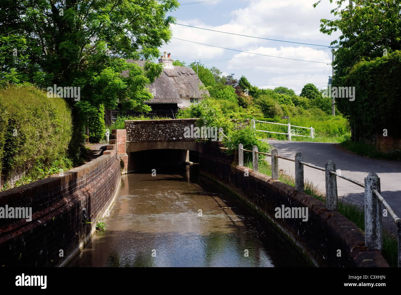 small village stream with traditional thatched cottage in background ...