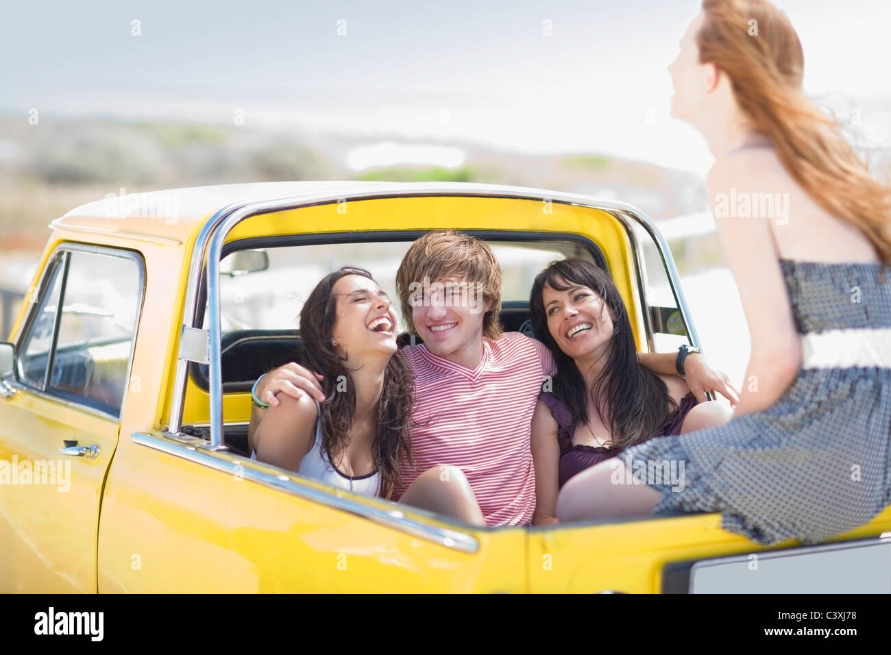 Young people sitting on back of pickup Stock Photo - Alamy