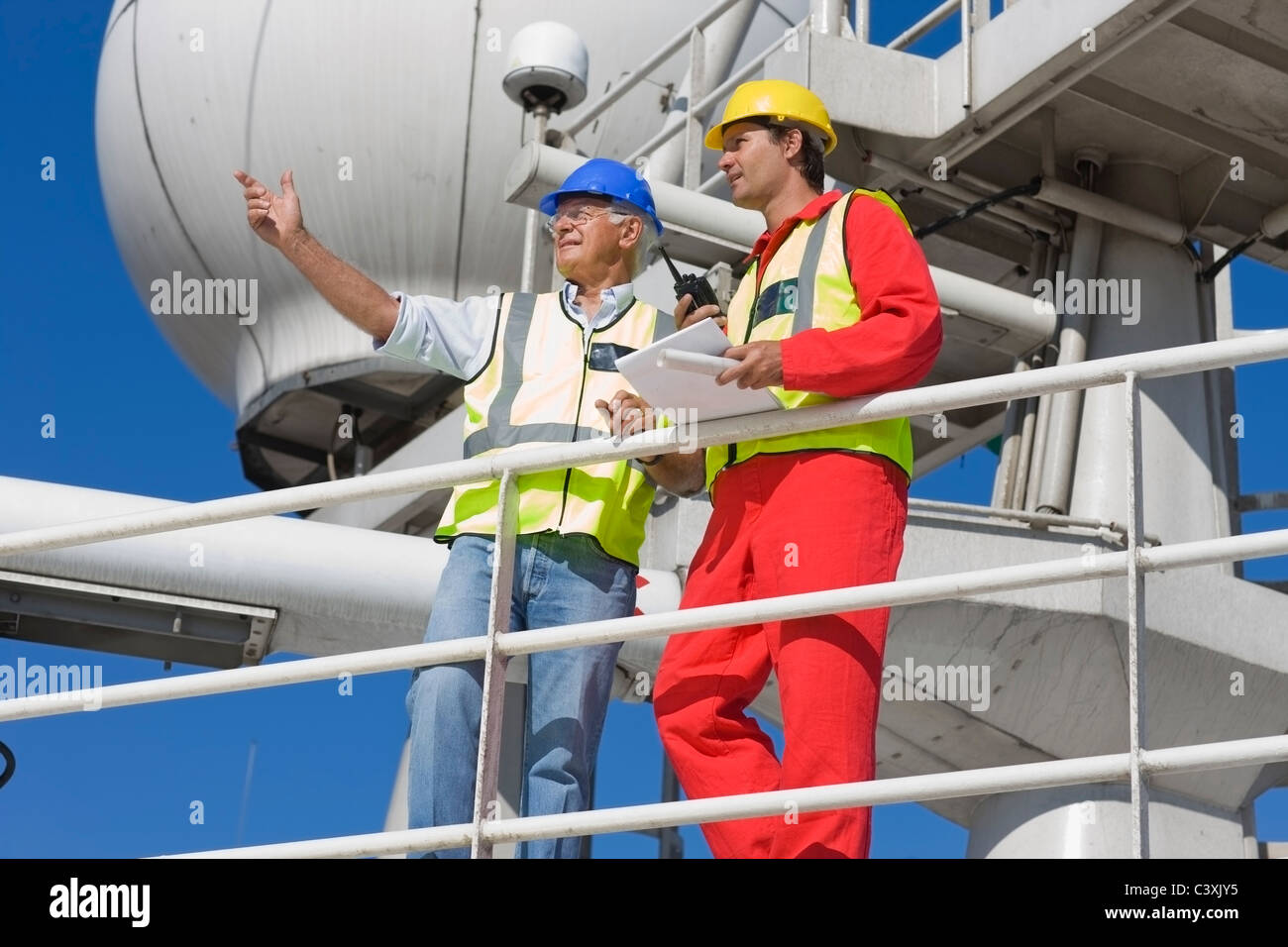 Two workers standing on guardrail Stock Photo - Alamy