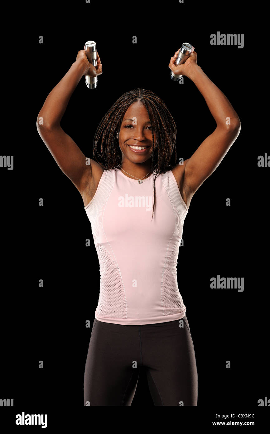 African American woman exercising with dumbbells isolated over black ...