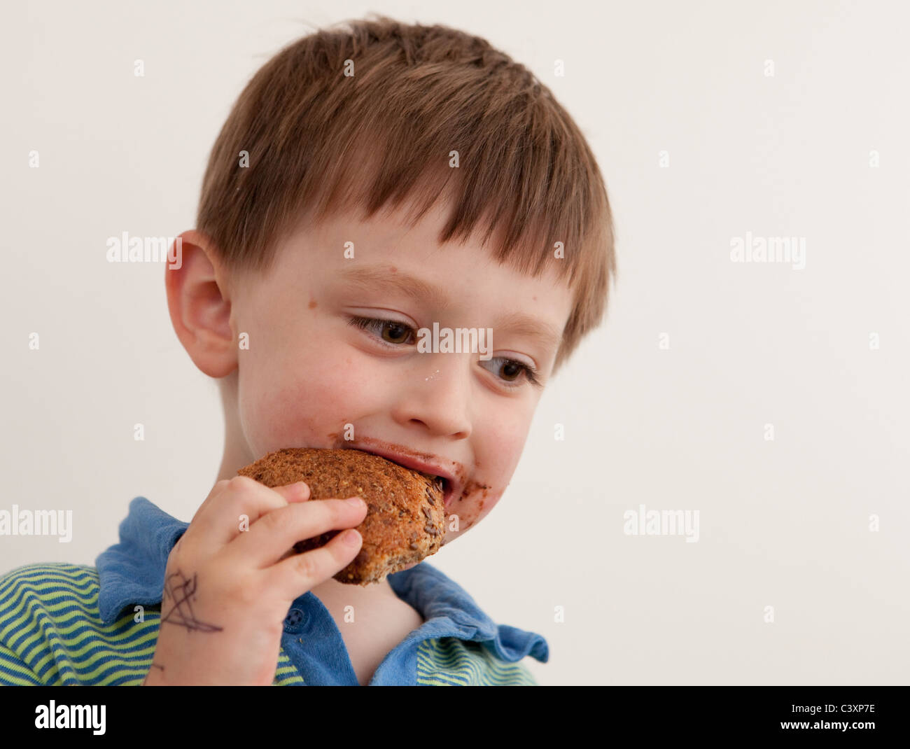 Young boy eating a chocolate biscuit Stock Photo - Alamy