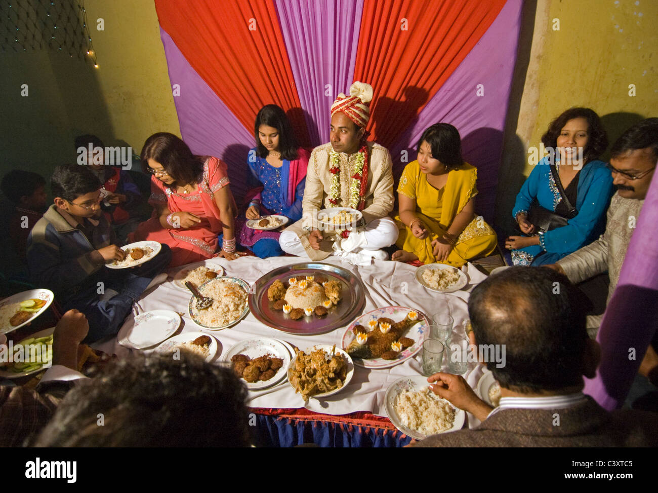 Guests sit around the groom during the meal at a muslim wedding Stock ...