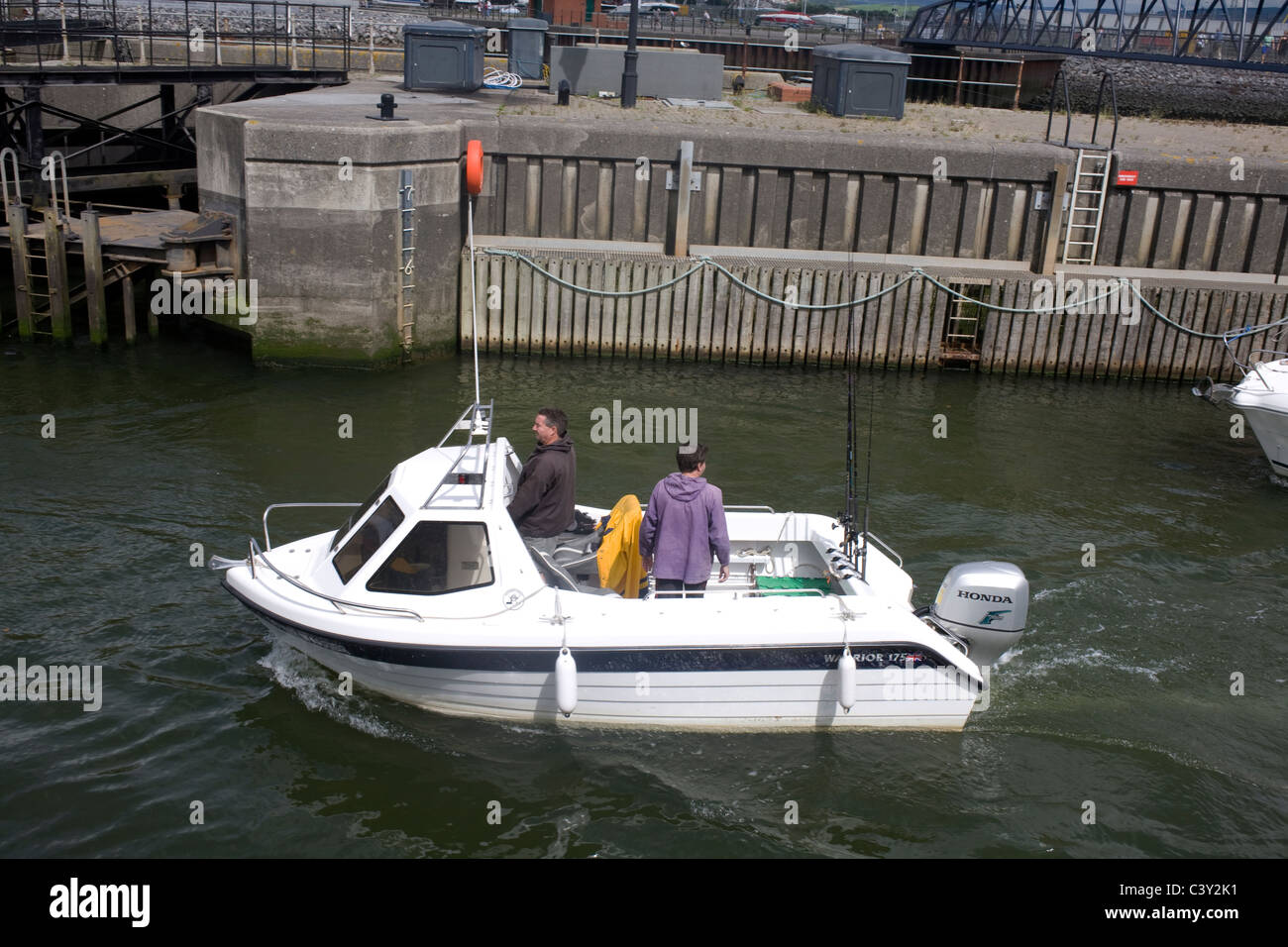 In Swansea, West Glamorgan, Wales, a motor dinghy leaves confines of ...