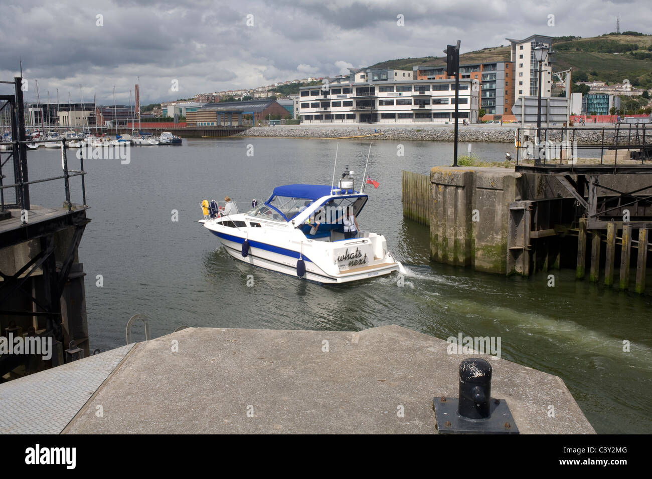 In Swansea, West Glamorgan, Wales, a power boat leaves confines of lock ...