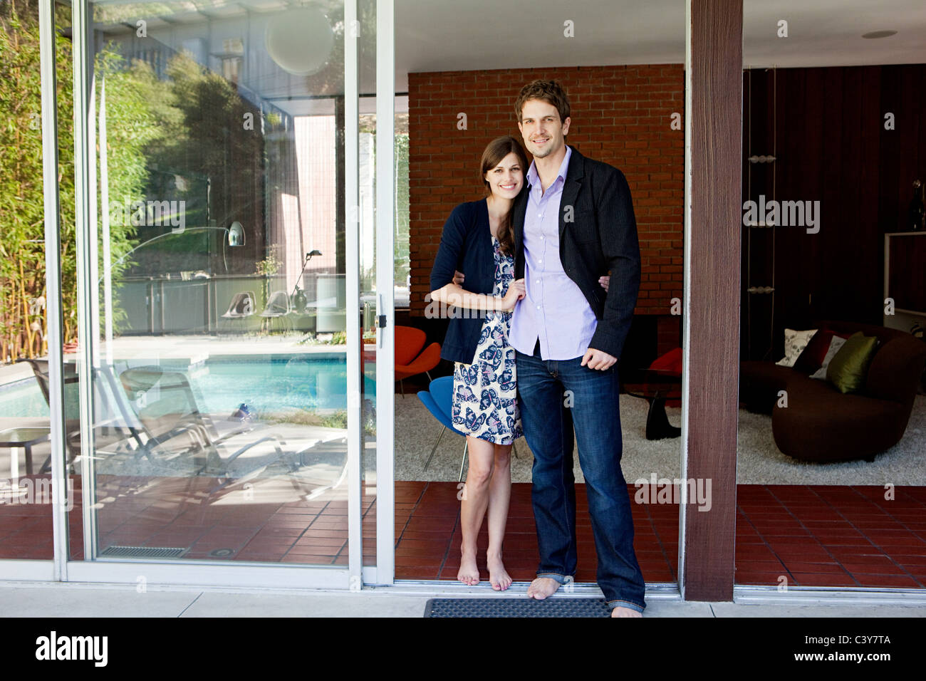 Couple standing by patio door, portrait Stock Photo - Alamy