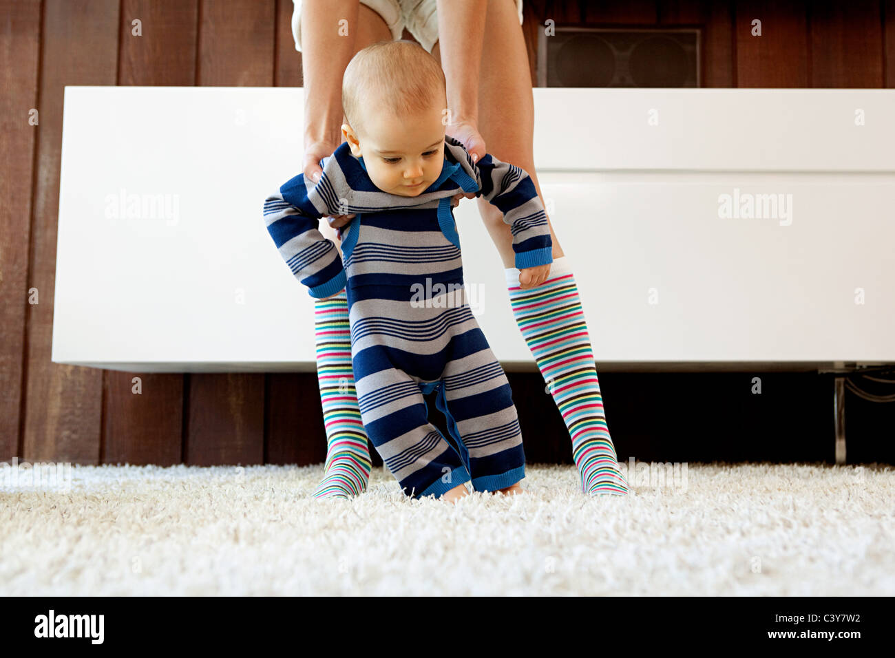 Mother helping baby son take first steps Stock Photo - Alamy
