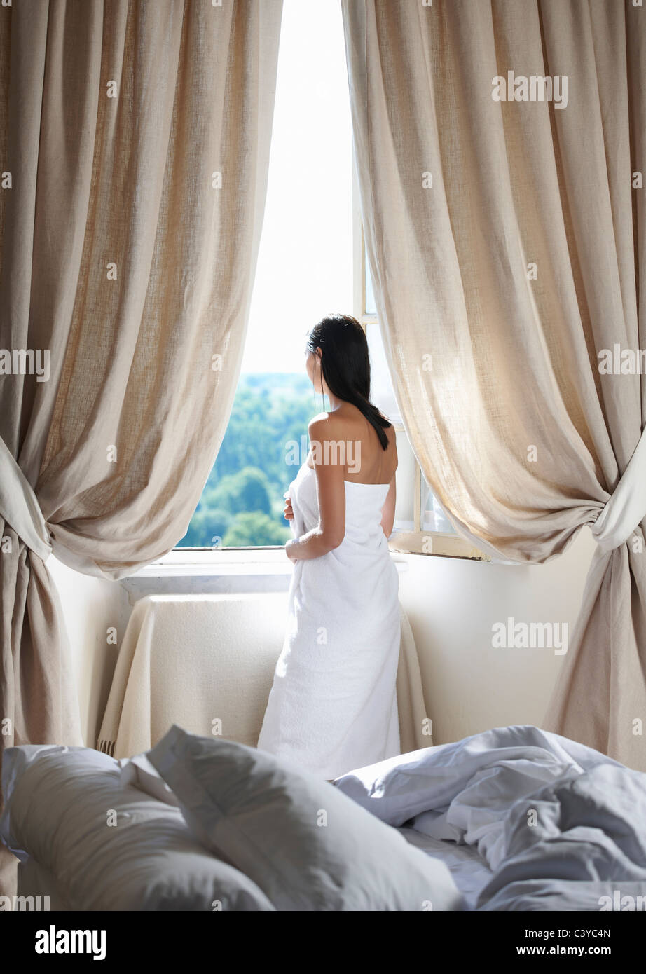 Woman standing by the window in towel Stock Photo - Alamy