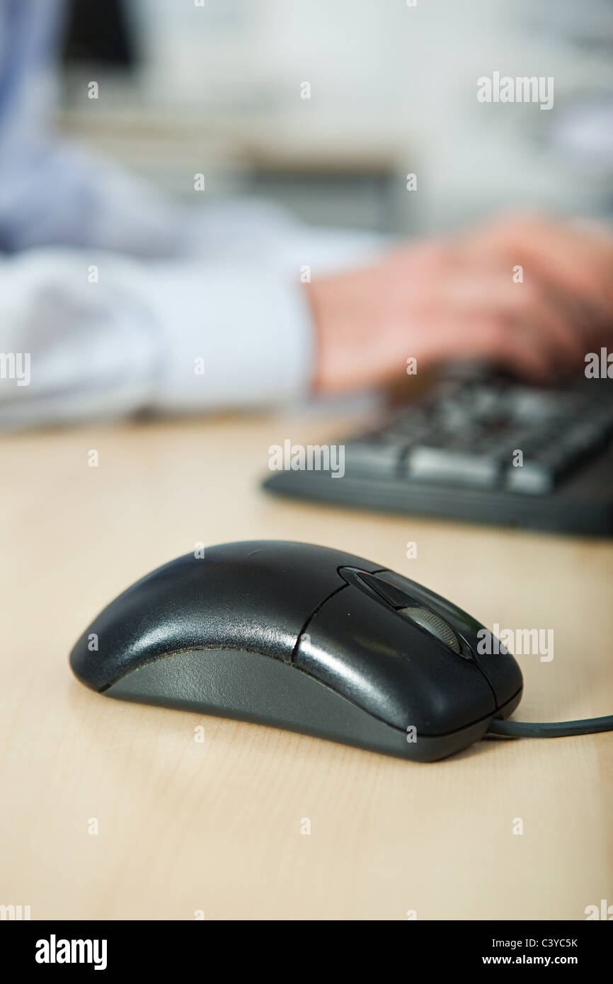 Office worker using computer, mouse in foreground Stock Photo - Alamy