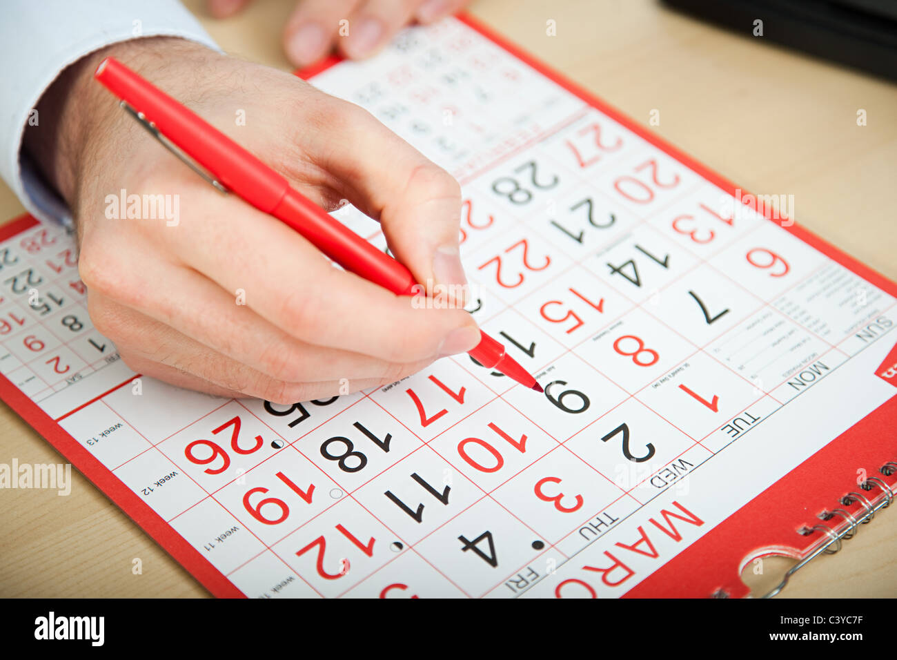 Office worker marking calendar with red pen Stock Photo - Alamy