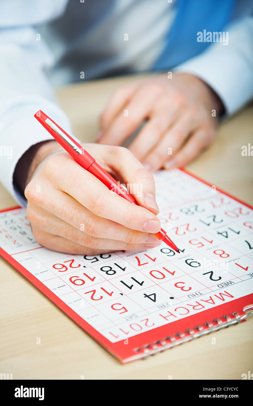 Office worker marking calendar with red pen Stock Photo - Alamy