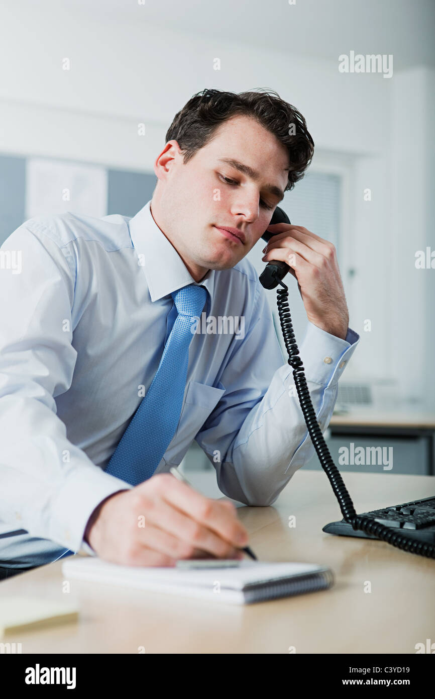 Office worker on telephone call, writing in notebook Stock Photo - Alamy