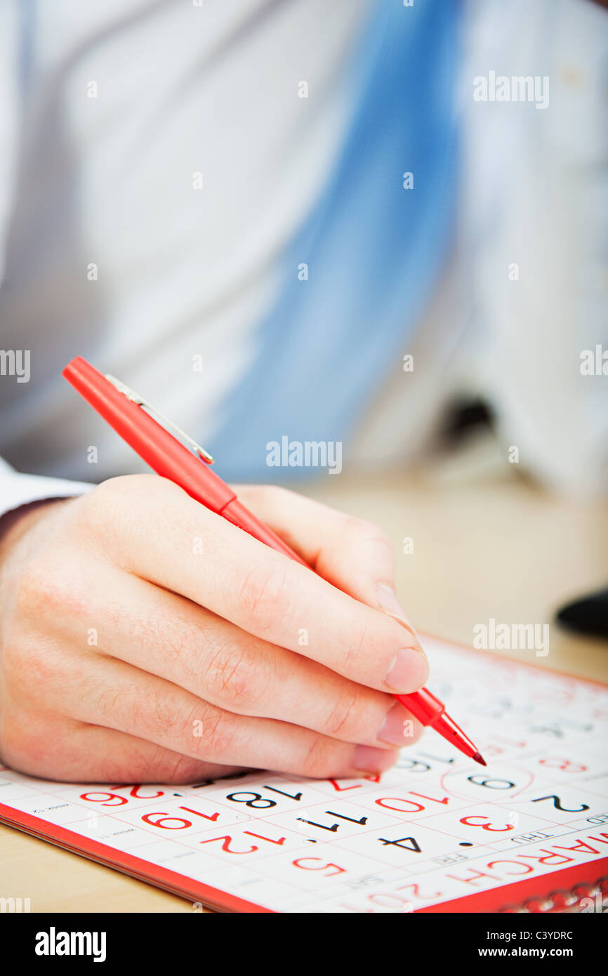 Office worker marking calendar with red pen Stock Photo - Alamy