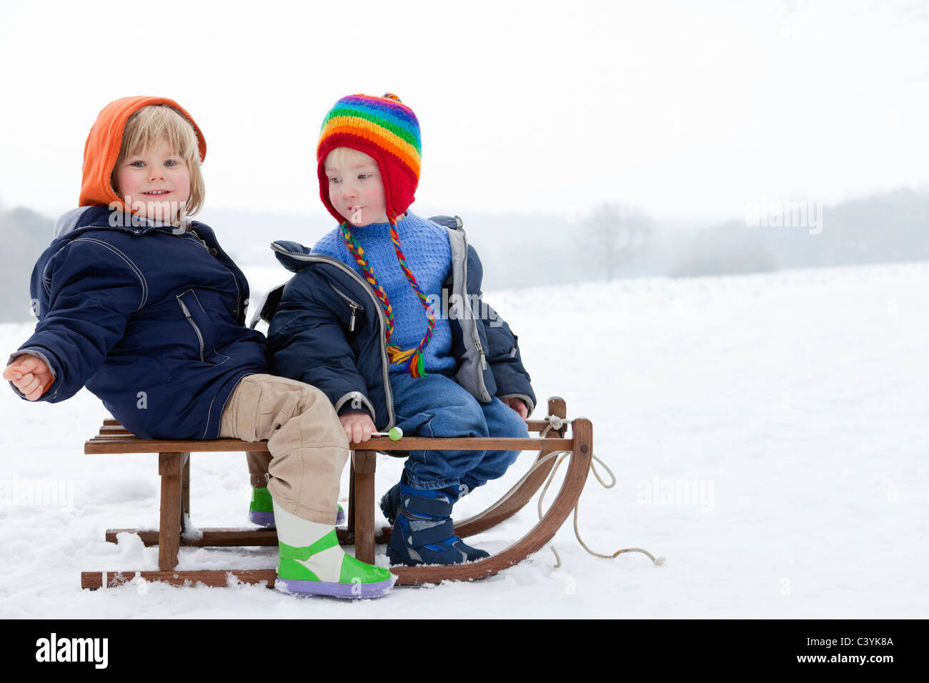 Two boys on a sledge in the snow Stock Photo - Alamy