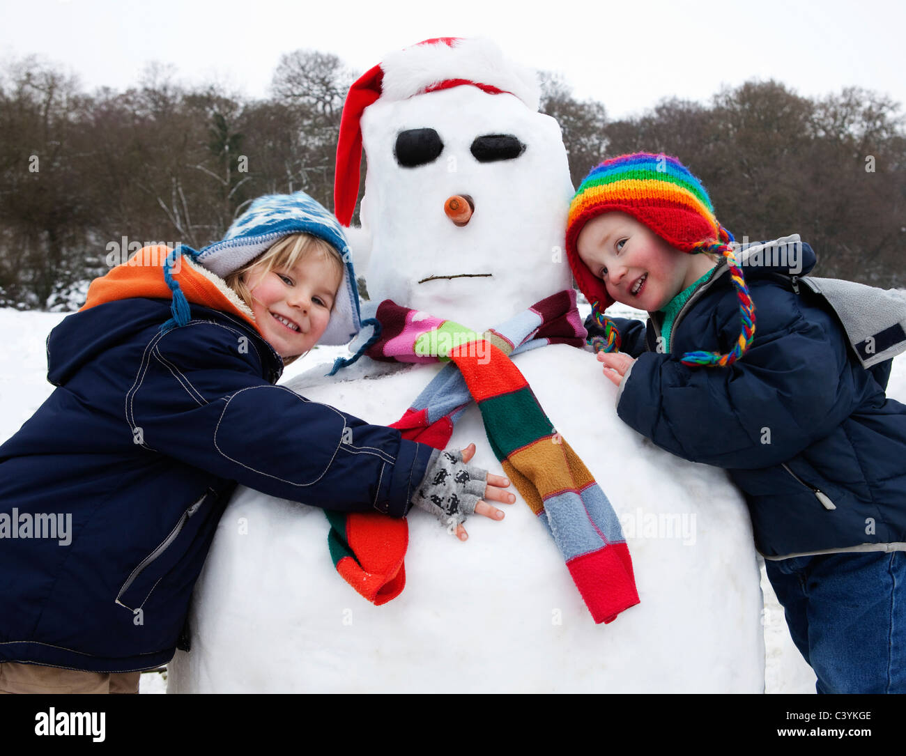 Two boys hugging a snowman Stock Photo - Alamy