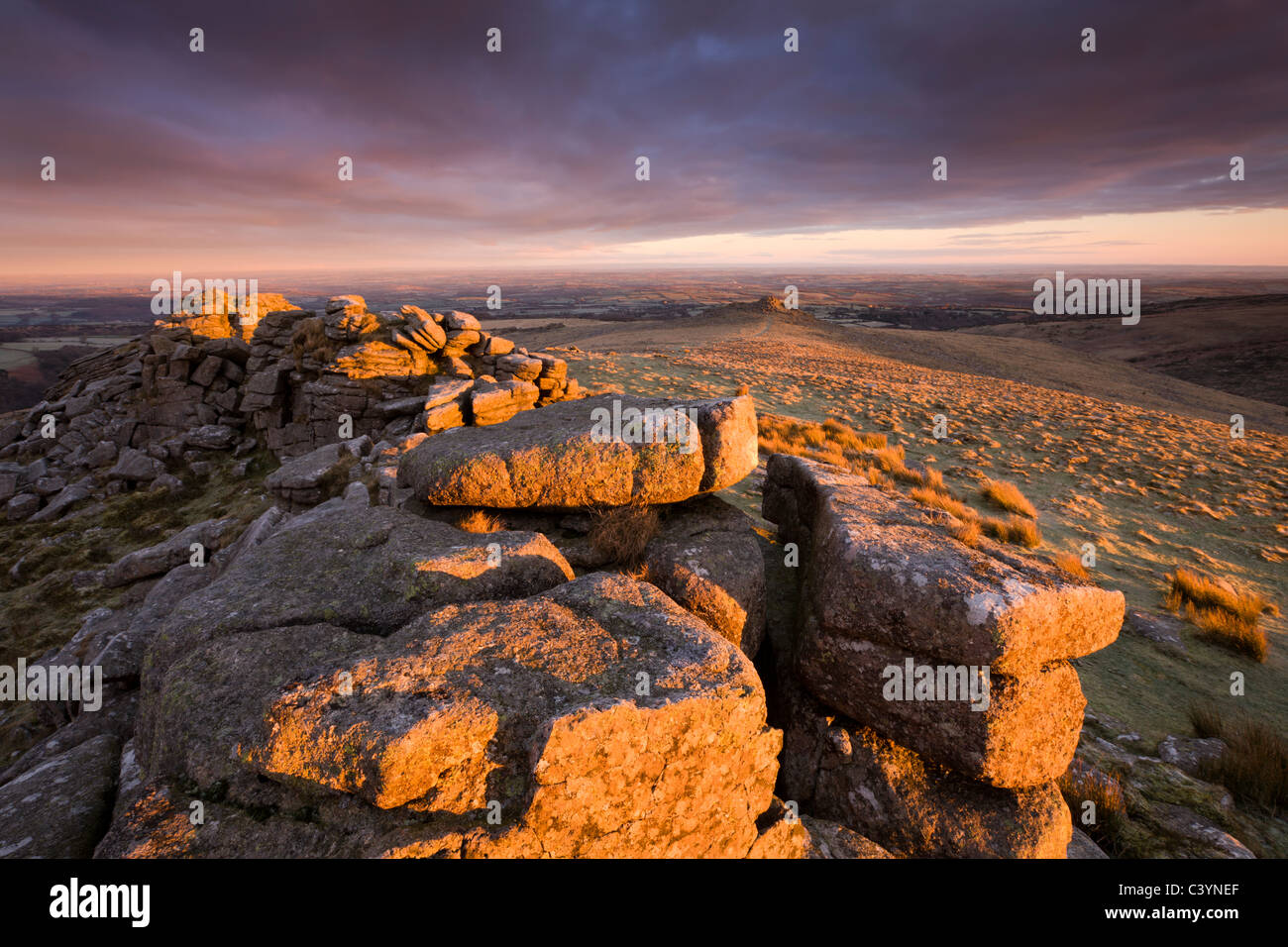 The first rays of early morning sunlight bathe Higher Tor in a rich ...