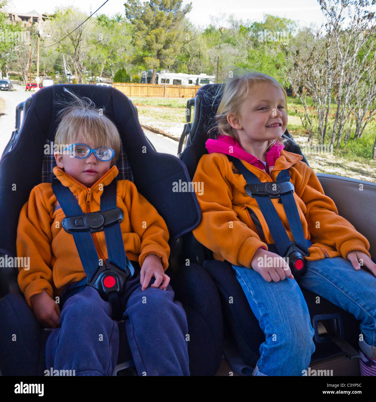 Two young children in car seats in the rear of an open sided off road ...
