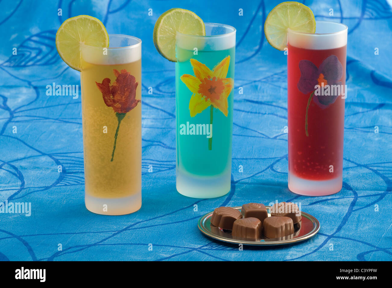 Three coloured drinks, each with a slice of lemon, and a selection of ...