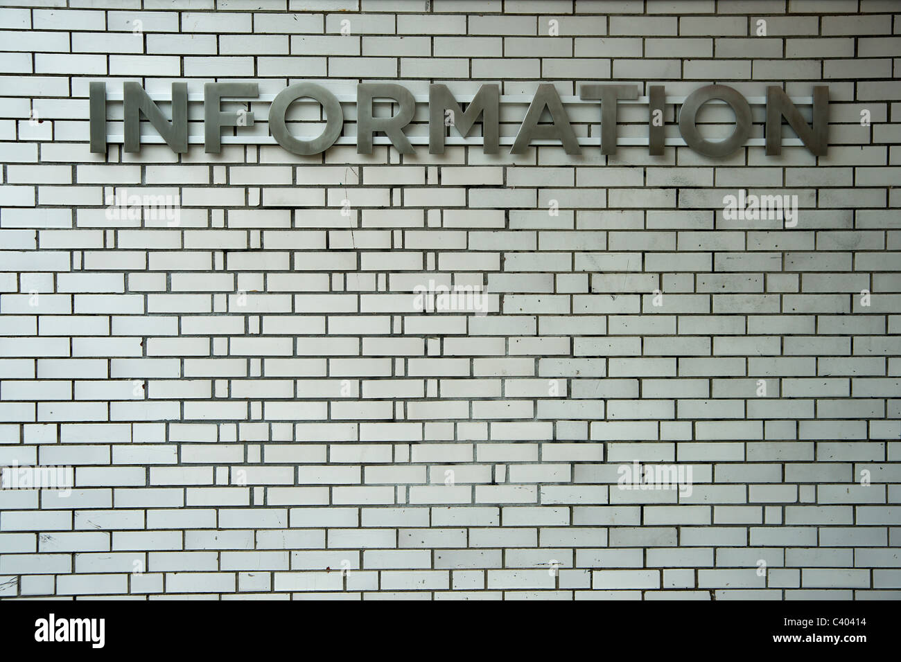 An old, metal information sign affixed to a white, brick wall Stock ...